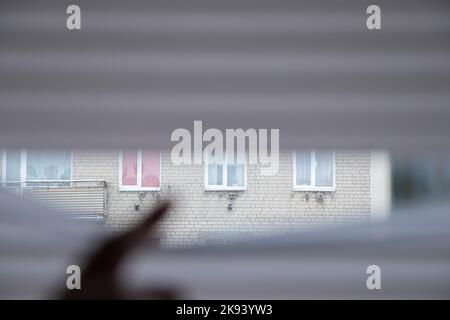 finger on the blinds on the window of the house, look out the window ...