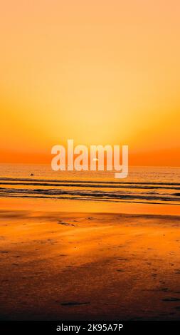 A vertical shot of a splendid sunset over the sea with a boat on the ...