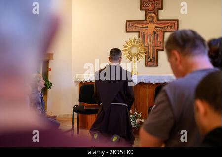 A Franciscan friar with the faithful adoring Jesus in the Most Blessed ...