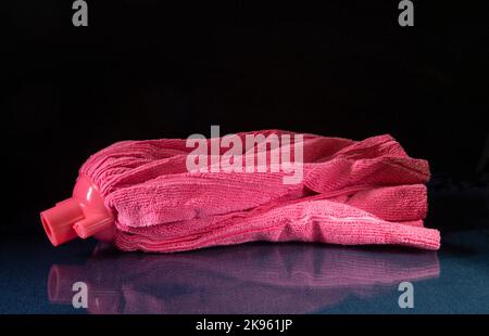 A pink microfiber mop head on a glass table. Household items with ...