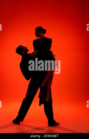 Man and woman, professional tango dancers in stylish, beautiful stage costumes performing over ...