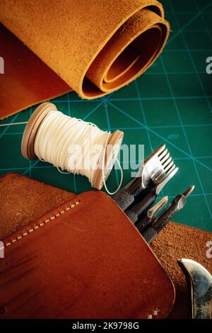 A closeup shot of thick leather sheets and tools for leathercraft on ...
