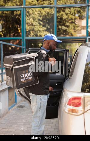 Young deliveryman carrying takeaway backpack, standing over full body ...