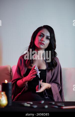 Fortune teller shuffling deck of tarot cards at grey table indoors ...