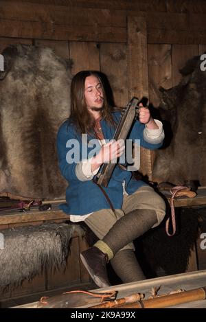 Viking actor playing a string instrument in a Viking chieftain's ...
