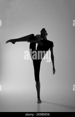 the silhouette of a rhythmic gymnastics girl in a bodysuit shows an ...