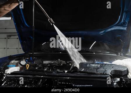 Pouring water on car engine. Washing car engine with spray, brush and ...