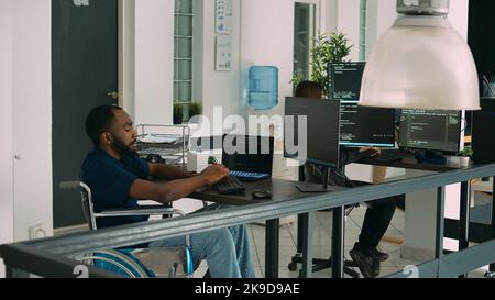 Web developer with physical disability writing code, computing big data to create app interface ...