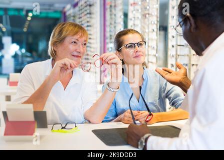 Male and female opticians helping client to choose a spectacles Stock ...