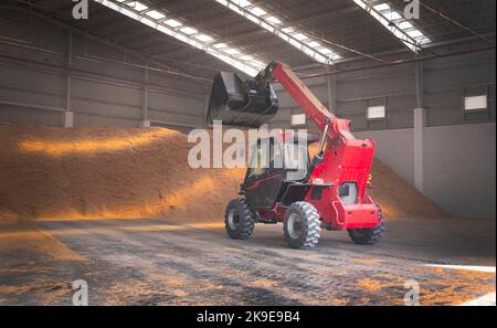 A close-up view of a truck unloads rice husks inside a warehouse ...
