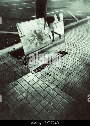 The shadow of a pedestrian is reflected in the wet pavement in the CBD ...