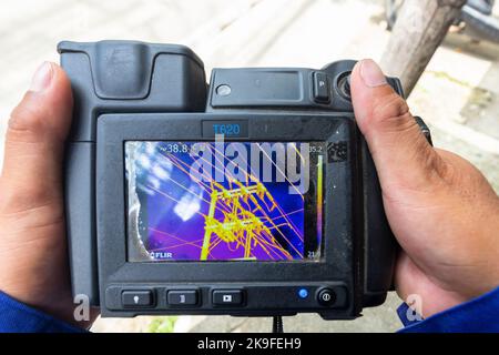 A Filipino electric utility worker using a thermal camera to check a ...
