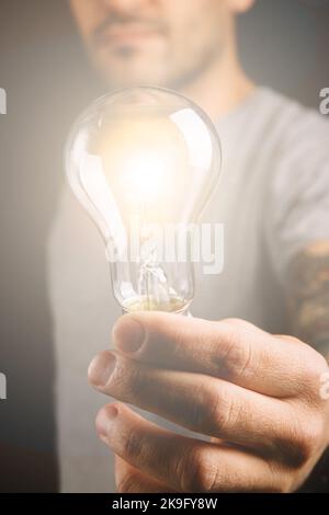 Man's hand holding lighted light bulb Stock Photo - Alamy