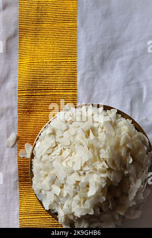 Close-up of raw poha/beaten rice/flattened rice in a brass Uruli/vessel ...