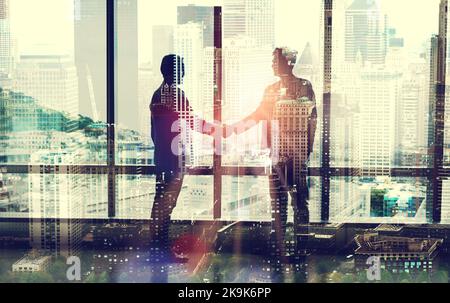 Merge and make it work. two young businessmen shaking hands ...