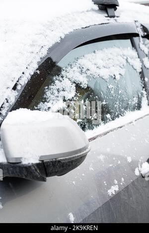 First snow covered car, close up. Car parked on the street at snowy day ...
