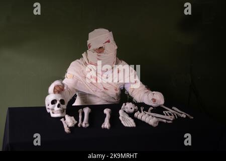 Bandaged mummy in a sitting position with black background on Halloween ...