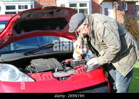 Man topping up the water levels in his radiator and screen wash of his ...