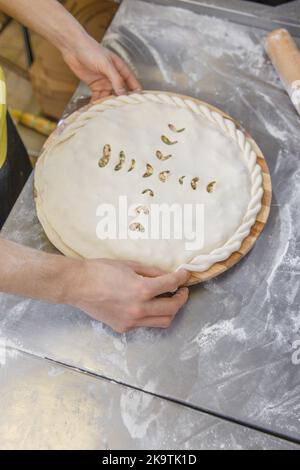 Hands closing the Ossetian pie stuffed with minced meat on the metal ...