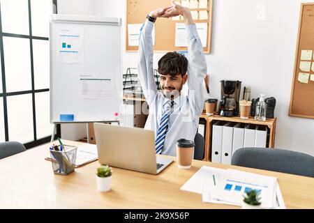Young hispanic businessman relaxed stretching arms at the office Stock ...