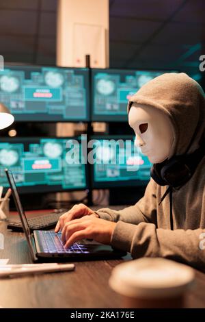 Male masked scammer stealing information from database program, hacking computer hardware system ...