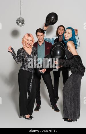 happy queer people with black balloons and champagne glasses looking at ...