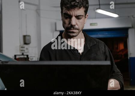 Car mechanic working on laptop in workshop Stock Photo - Alamy