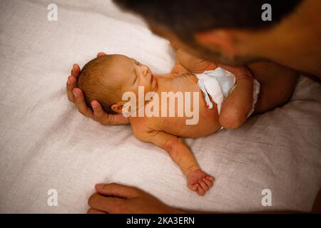 High angle of unrecognizable bearded dad gently putting adorable infant ...