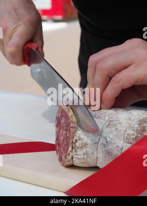catering and waiting staff hand with knife slicing salami ham in a ...