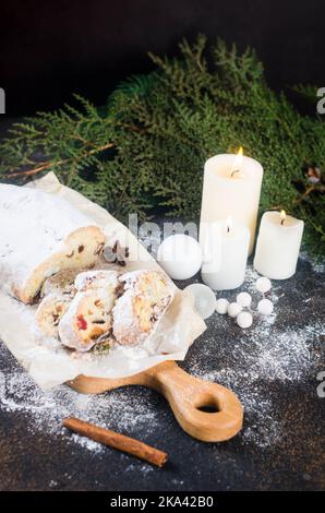 Stollen sliced on kraft paper on dark wooden table with xmas tree ...
