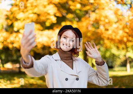 Smiling caucasian millennial red-haired lady in raincoat and beret ...