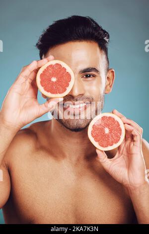Face portrait, skincare and man with grapefruit in studio isolated on a gray background ...