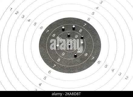 Black air gun pellet gun laying on a paper shooting target next to a ...