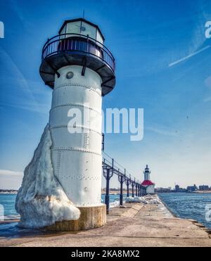 Snow covered landscape by the sea with a lighthouse and rock in sunset ...