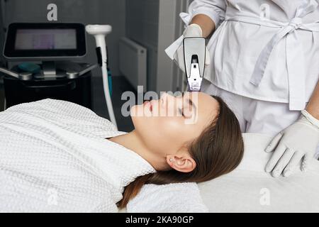 Pretty woman enjoying radiofrequency lifting procedure for her face ...
