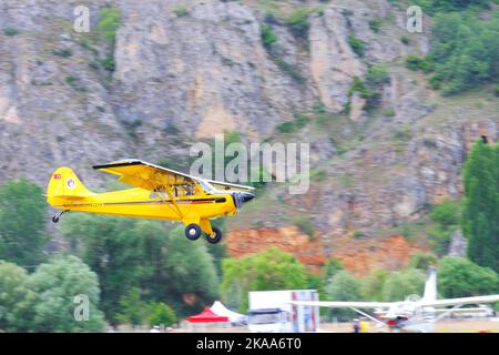 Yellow single engine plane approaching to the ground with rocks at the ...