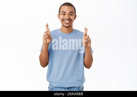 Hopeful young man cross fingers, wishing, praying and anticipating good ...