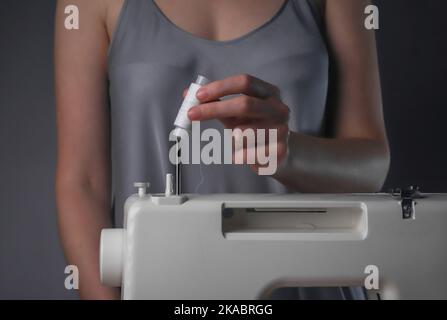 Female hands putting thread spool on sewing machine Stock Photo - Alamy
