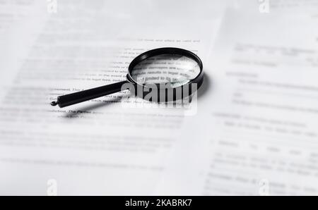 Magnifying glass lying over heap of paper documents. Investigation and ...