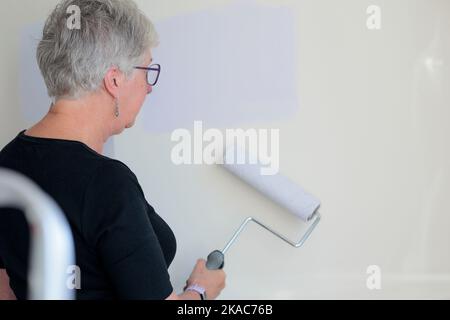 Mature woman starting to use paint roller on a wall Stock Photo - Alamy