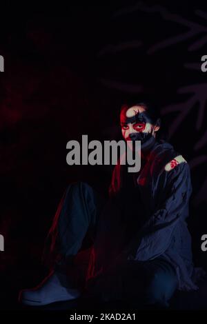 A scary zombie with blood and wounds on his body walking while eating a ...