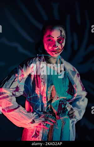 Young woman with glowing blue led band portrays bloodthirsty zombie ...