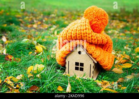 Chunky knitted hat put on a wooden cottage figurine placed on a green ...