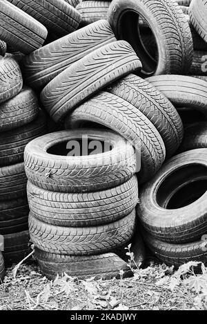 A vertical grayscale shot of many used old car tires Stock Photo - Alamy