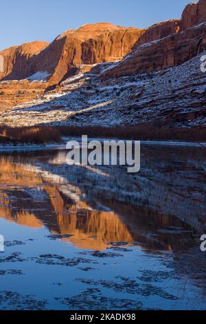 Orange sandstone cliffs reflected on the surface of the partially ...