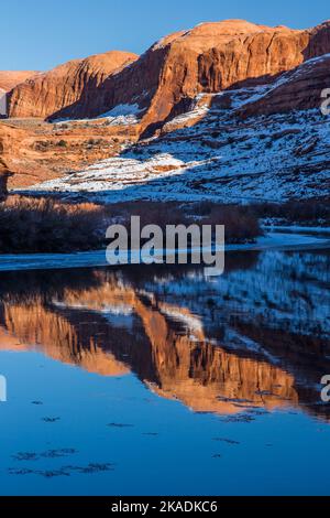 Orange sandstone cliffs reflected on the surface of the partially ...