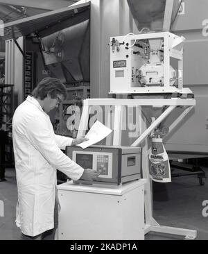 1980s, historical, male technican operating a machine's computer on a ...