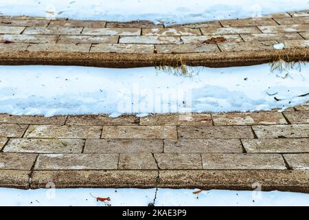 Paving paths in the park, covered with the first snow in winter. Winter ...
