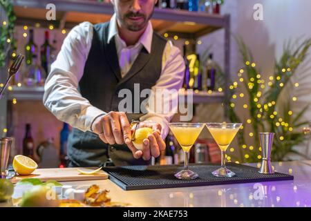 Handsome barman making elegant cocktail in night club on bar counter ...