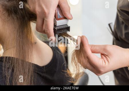 Polishing dark blond hair with a hair clipper closeup in a salon. The ...